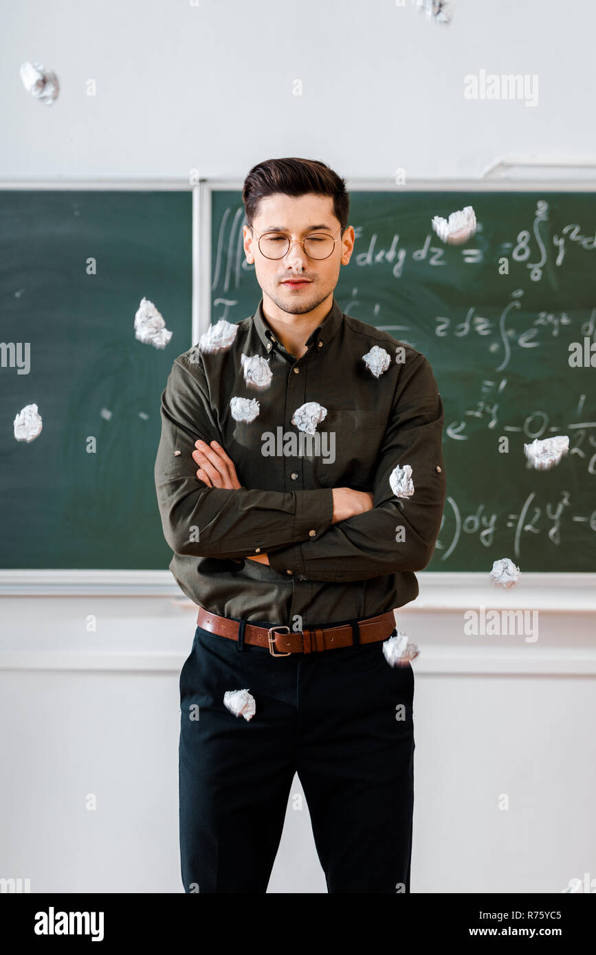 Crumpled Paper Balls Flying At Male Teacher With Arms Crossed In