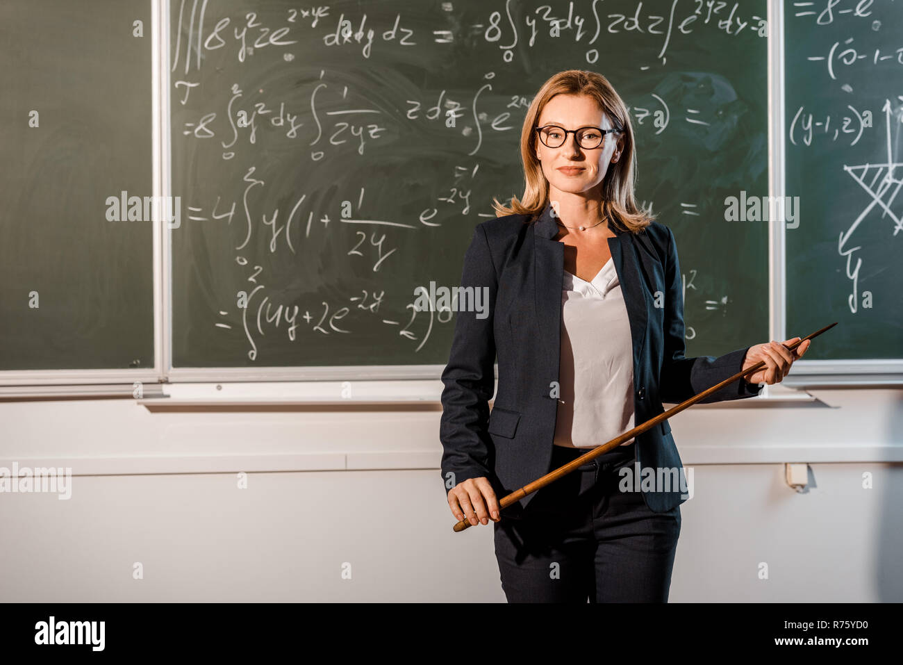 attractive female teacher with wooden pointer explaining mathematical ...