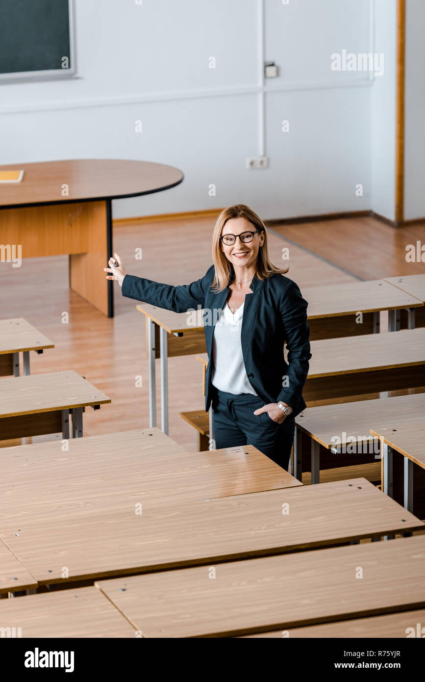 smiling female university professor with outstretched hand standing in ...
