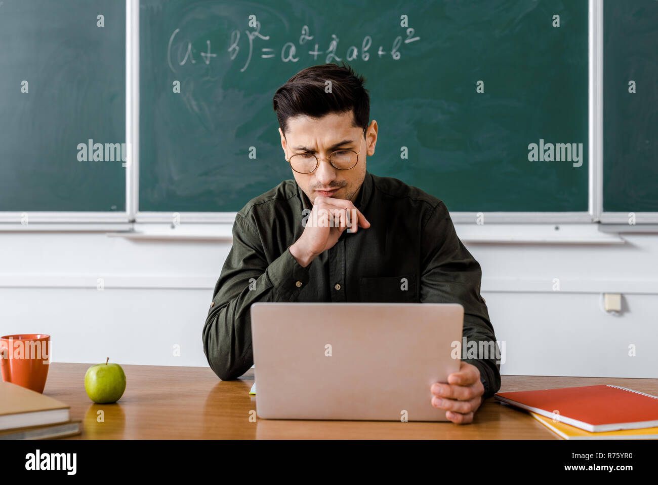 Teacher Using Computer And Desk