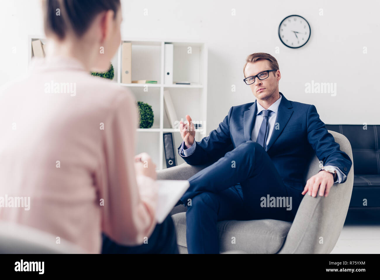 selective focus of handsome businessman in suit and glasses giving ...
