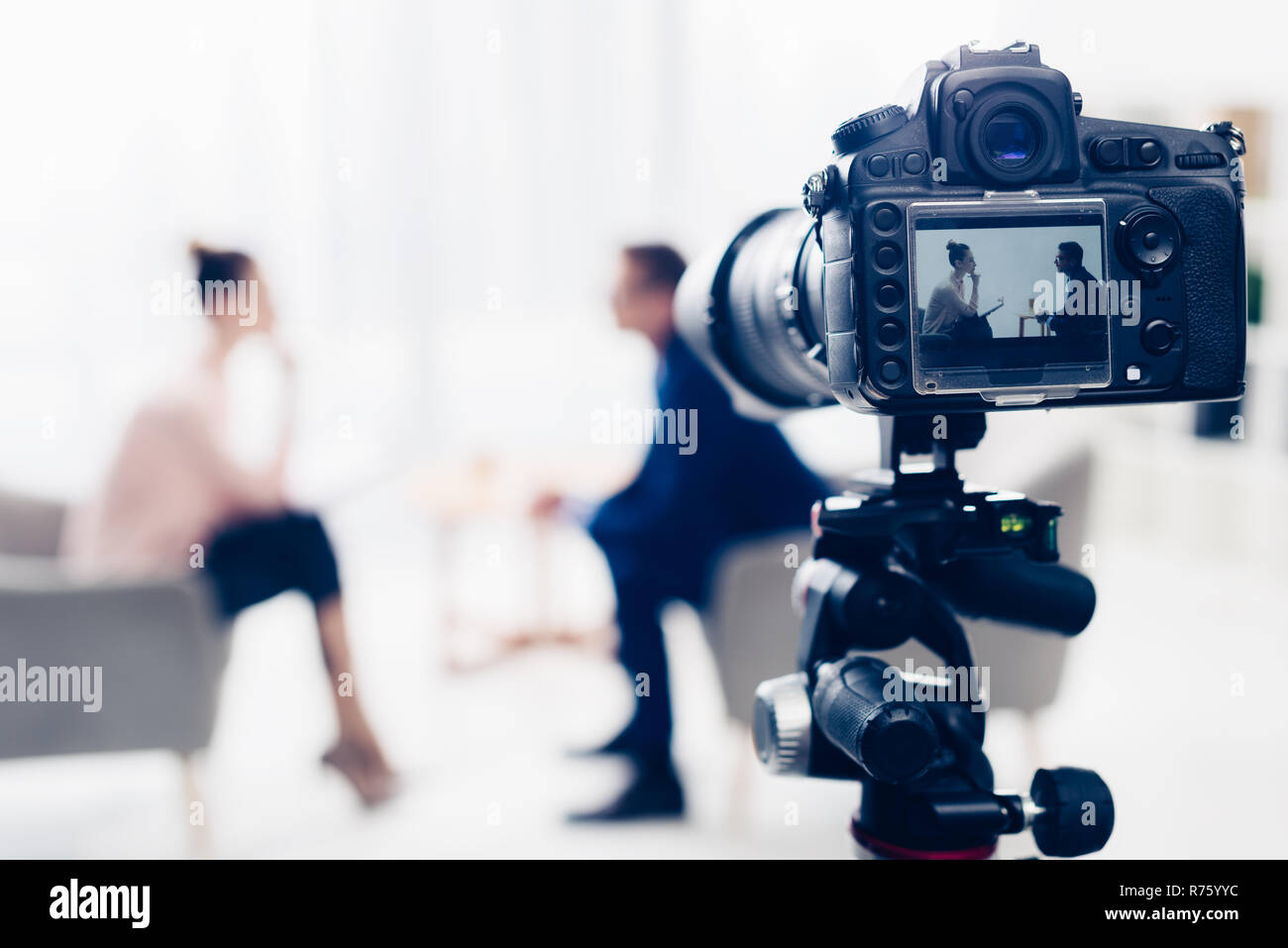 businessman giving interview to journalist in office, camera on tripod ...