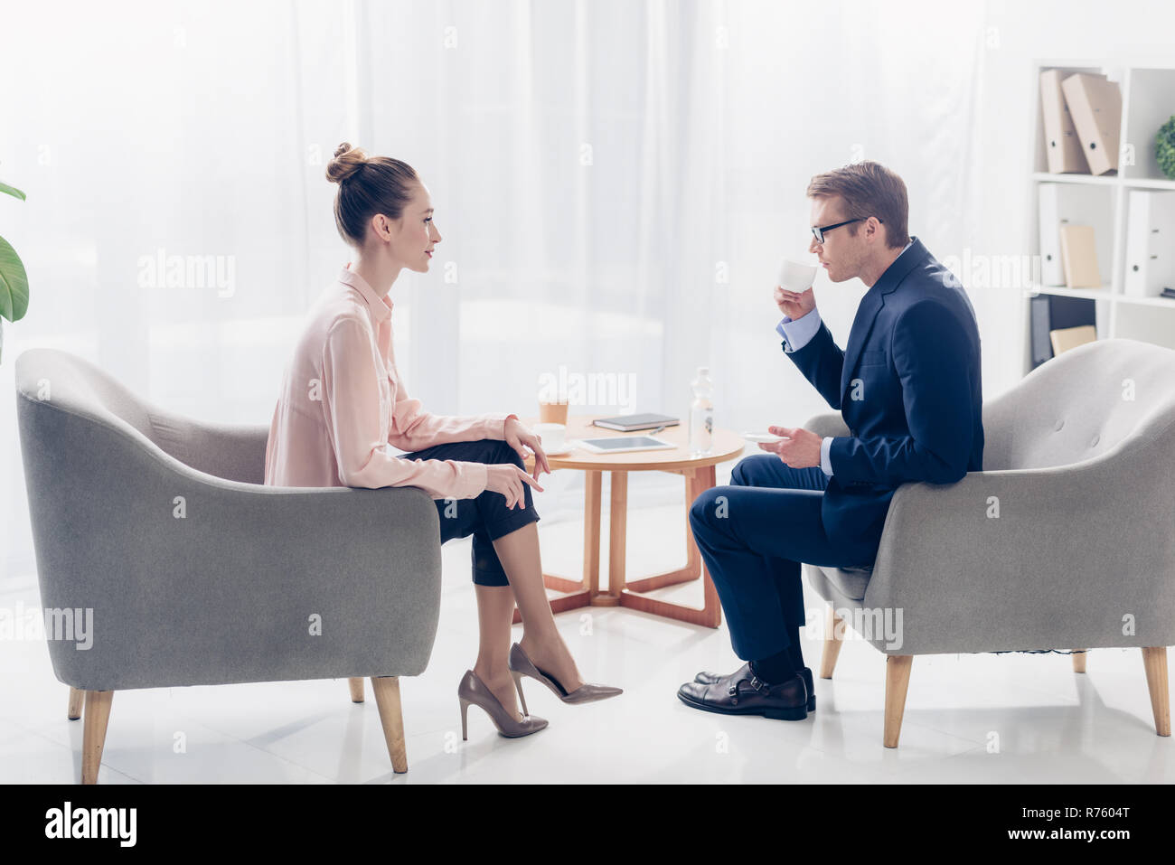 side view of handsome businessman giving interview to journalist and ...