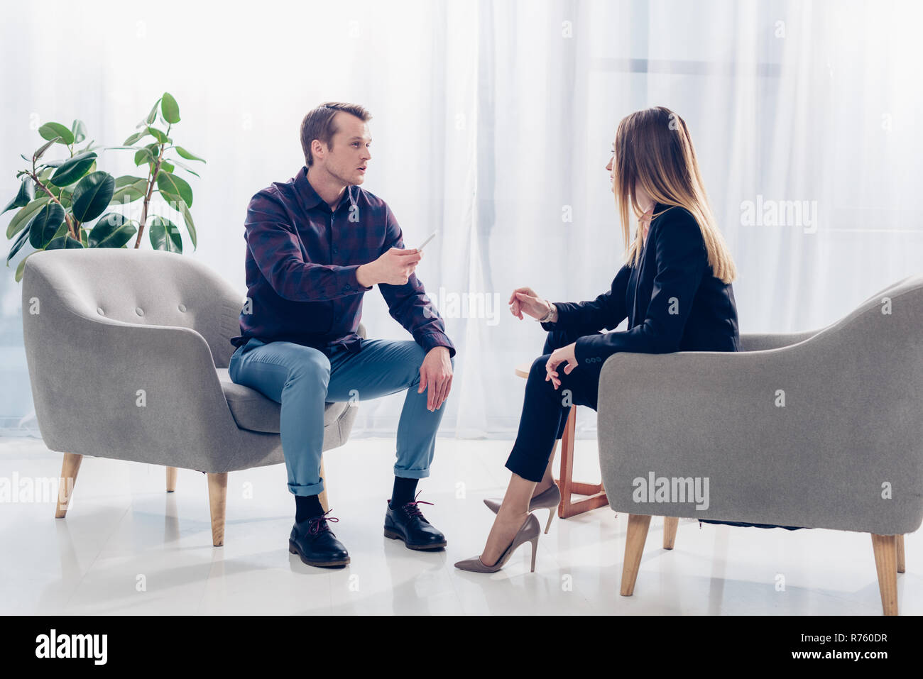 side view of businesswoman in suit giving interview to journalist in ...
