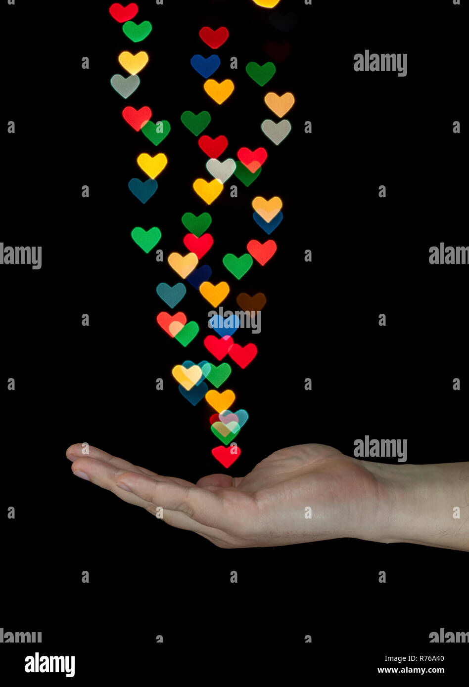 Human hand catching heart shaped bokeh created from decoration lights ...