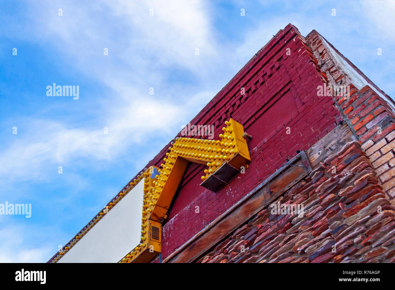 neon sign of a yellow arrow in a brick building Stock Photo - Alamy