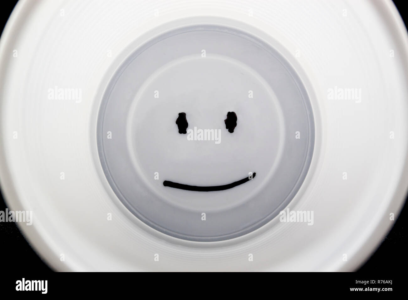 White plastic cup with a smiley face on the bottom Stock Photo - Alamy
