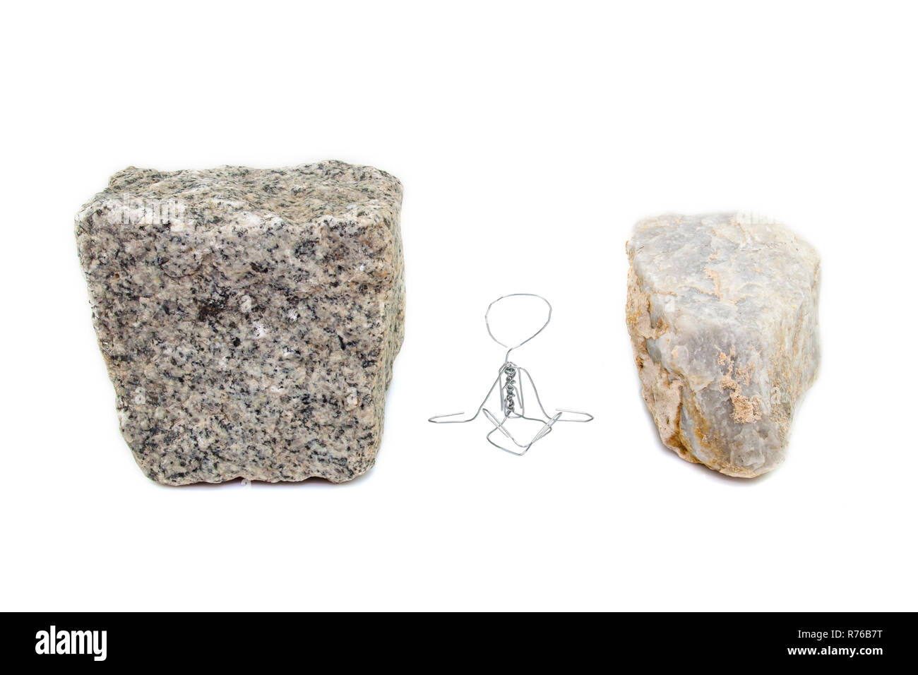 A paperclip figure sitting between paving stone and a marble stone ...