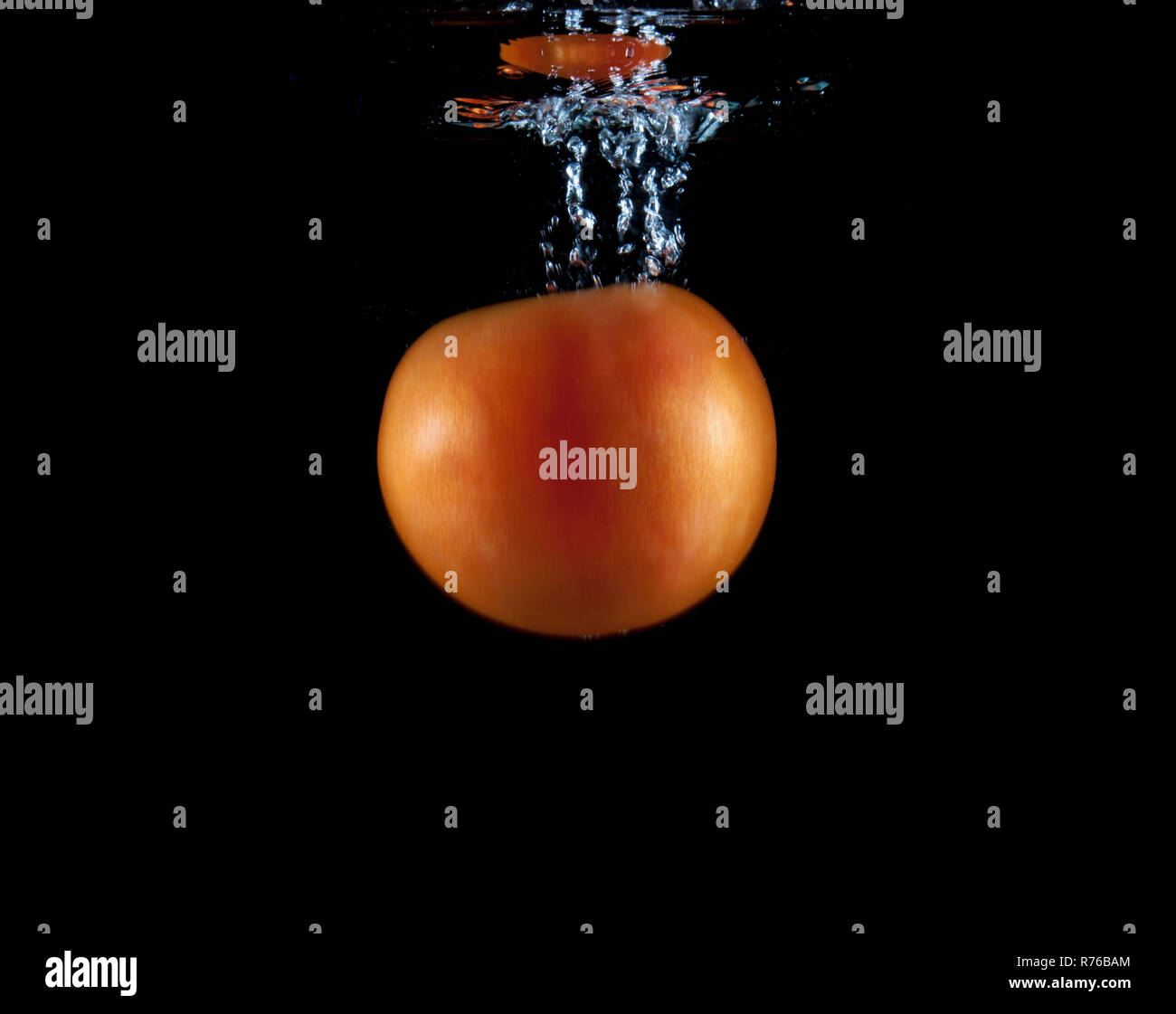 Whole red tomato sinking underwater Stock Photo - Alamy