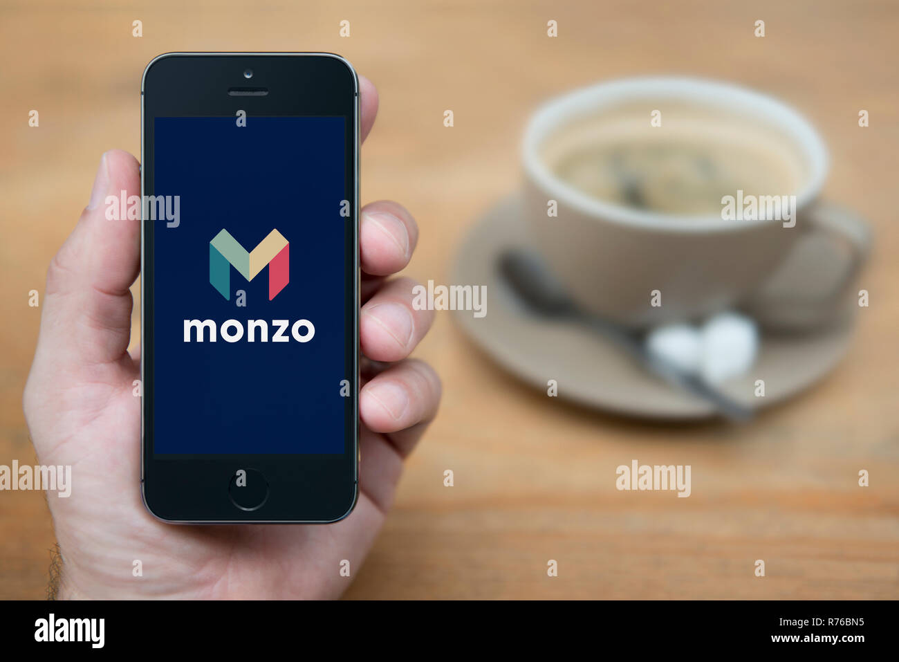 A man looks at his iPhone which displays the Monzo logo (Editorial use ...