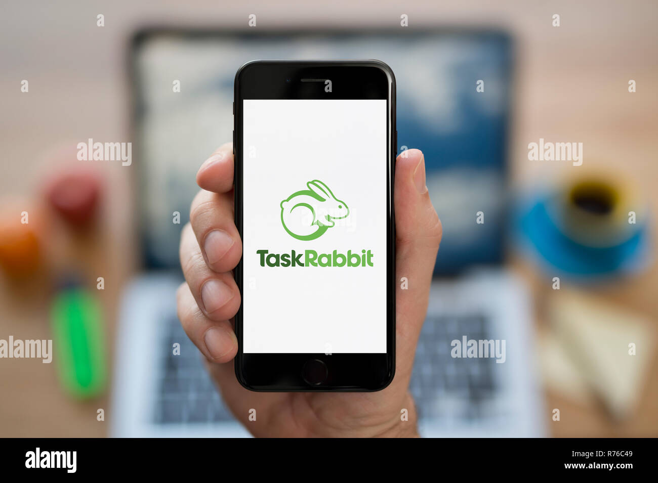 A man looks at his iPhone which displays the Taskrabbit logo (Editorial ...