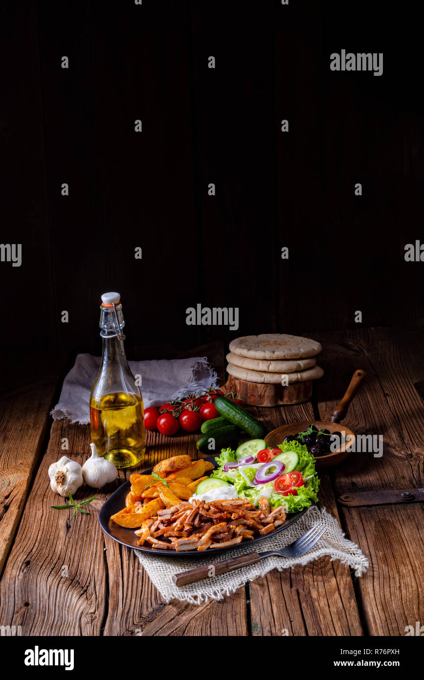 rustic gyros plate with green salad and potato wedges Stock Photo - Alamy