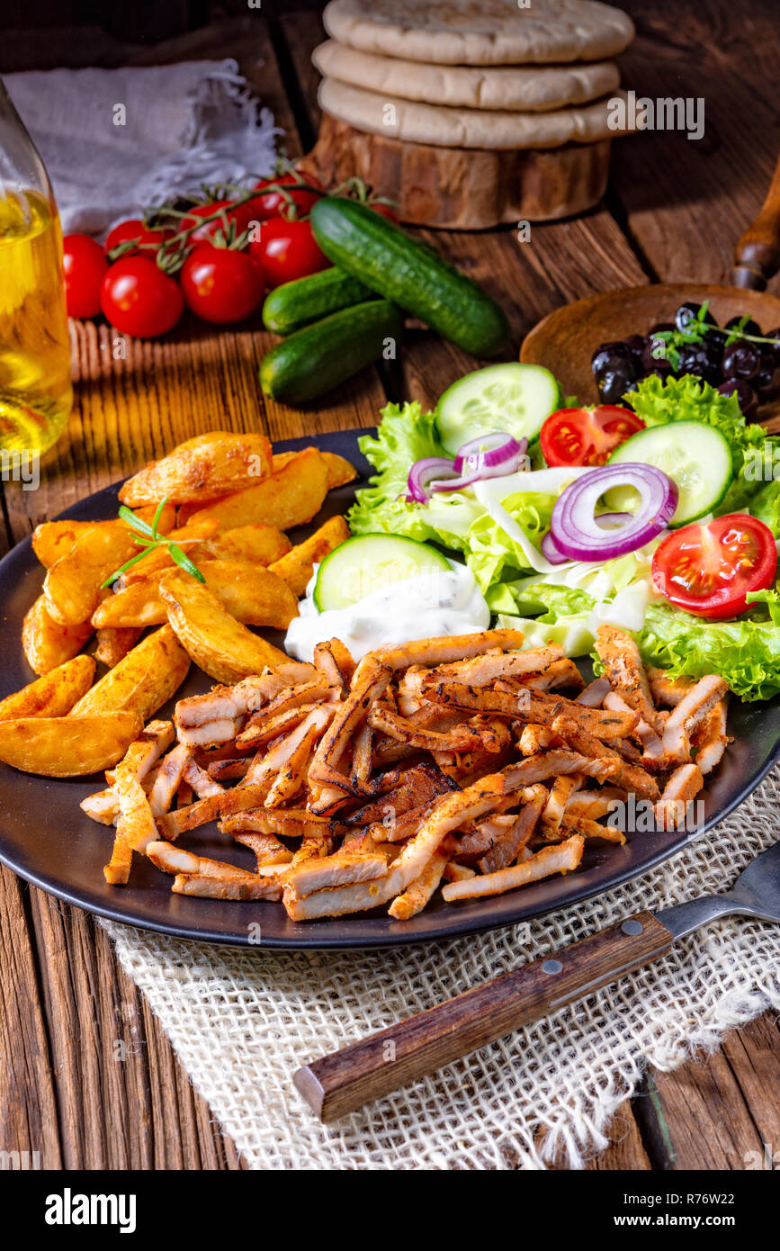rustic gyros plate with green salad and potato wedges Stock Photo - Alamy