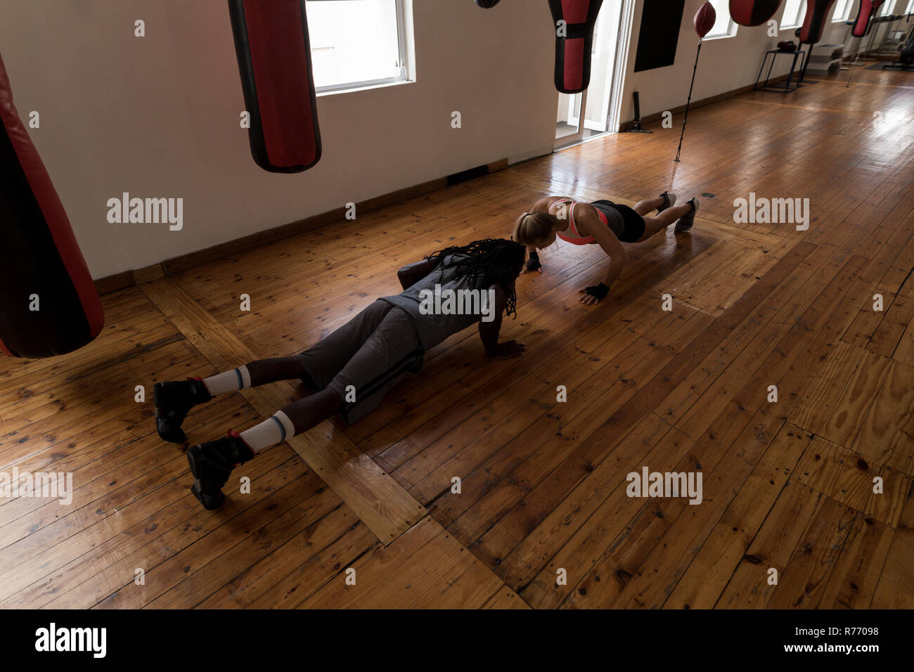 Trainer assisting female boxer in doing push ups in fitness studio ...