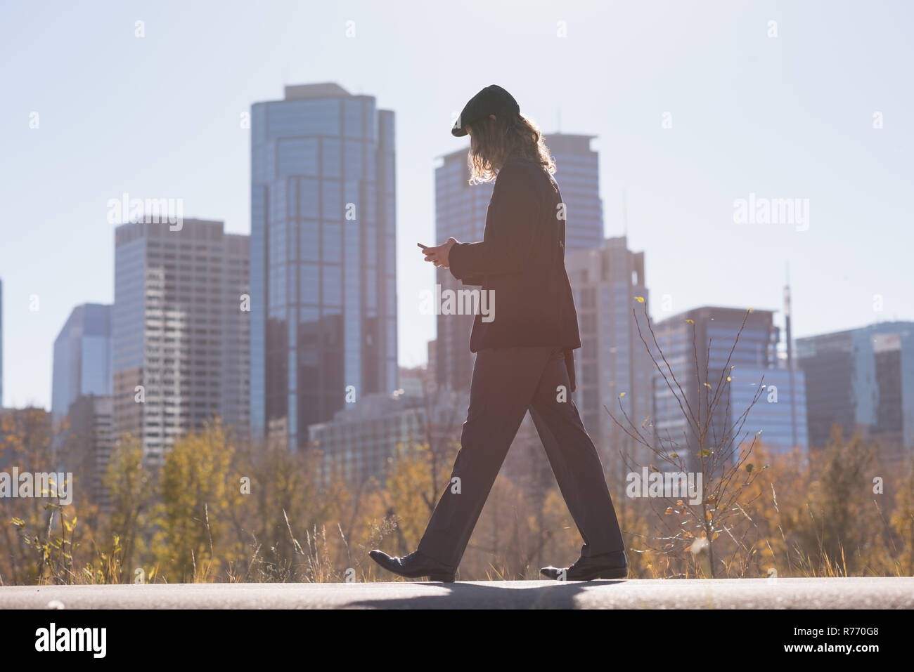 Man using mobile phone while walking on a road Stock Photo - Alamy