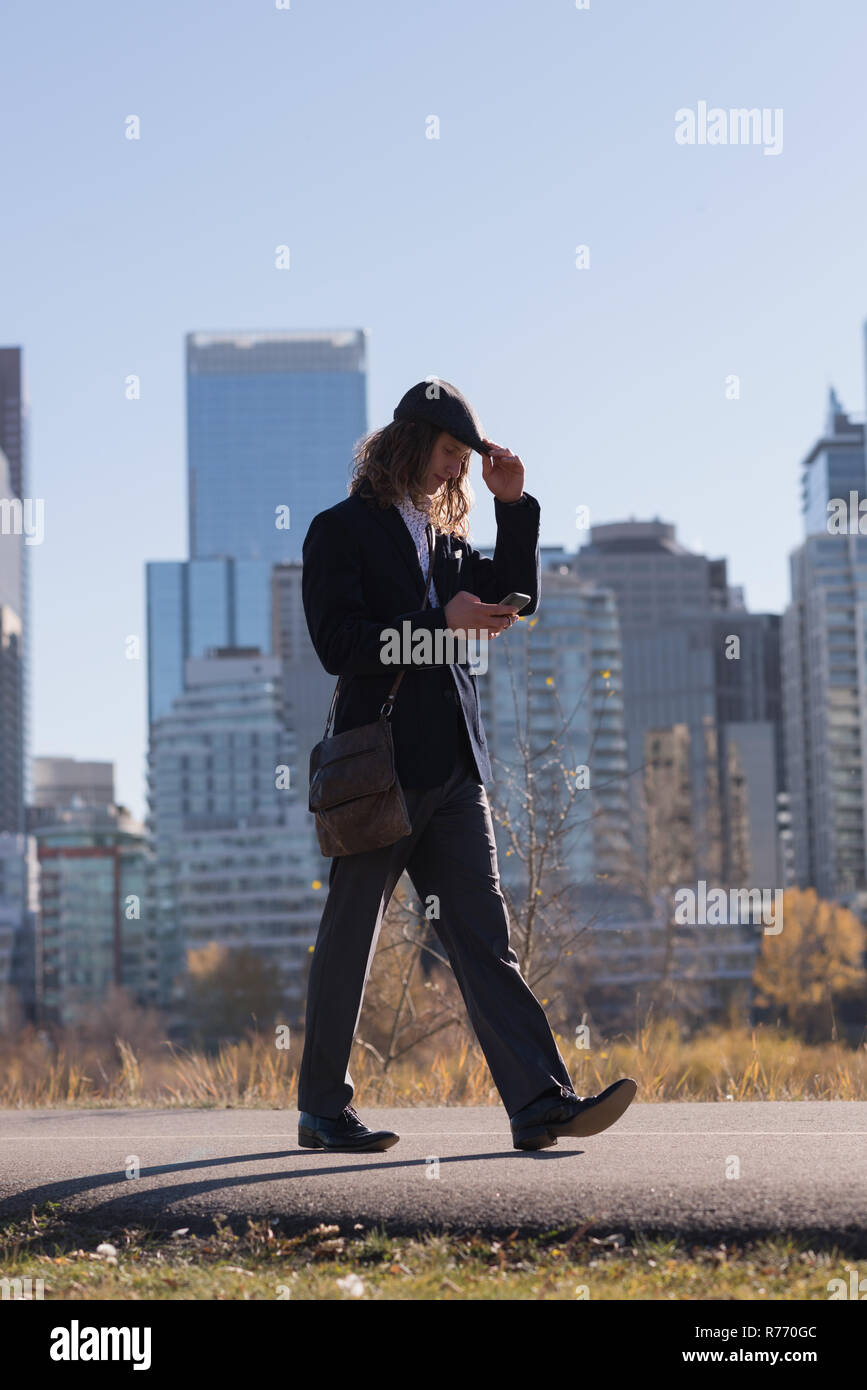 Man using mobile phone while walking on a road Stock Photo - Alamy