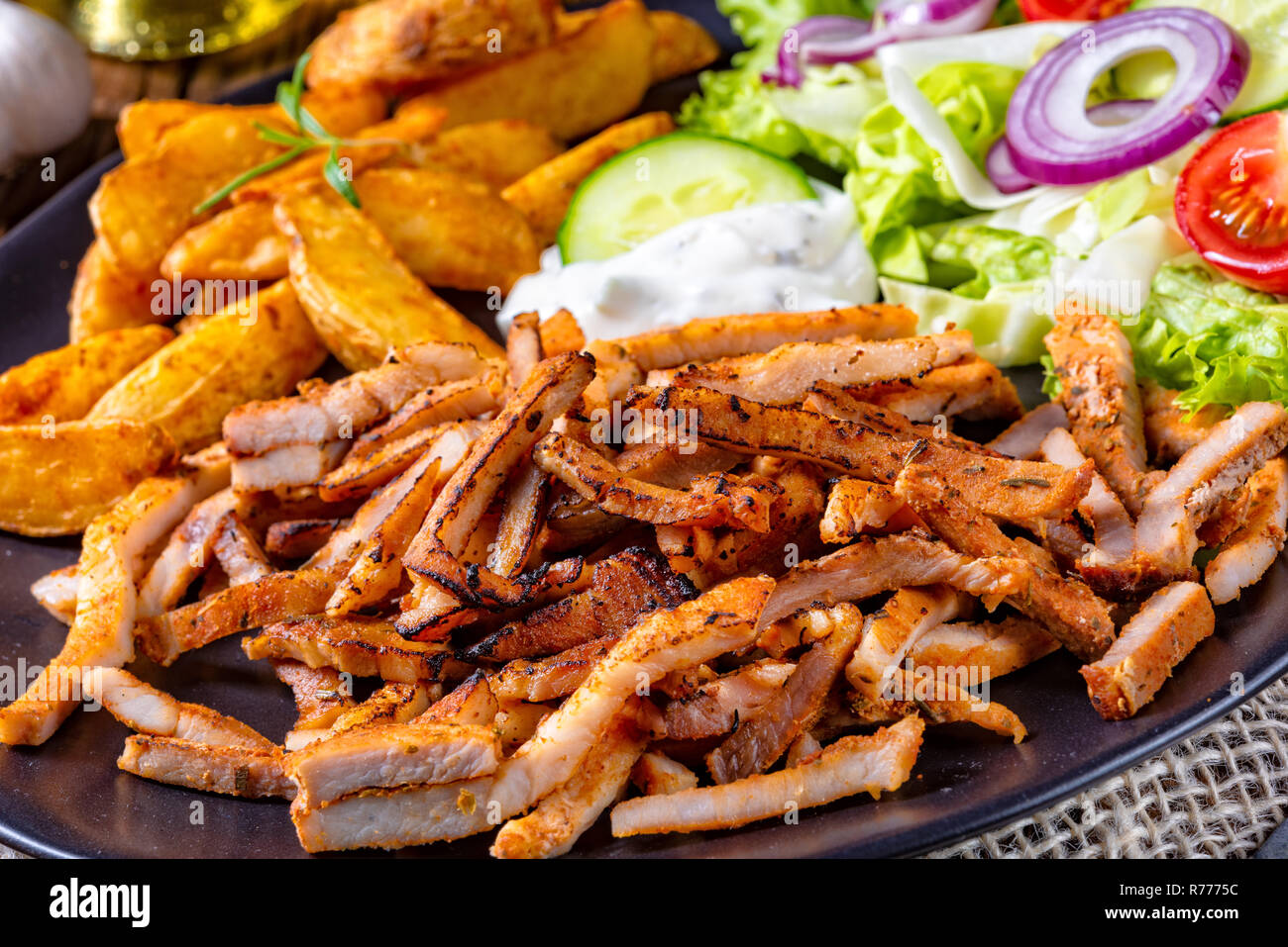 rustic gyros plate with green salad and potato wedges Stock Photo - Alamy