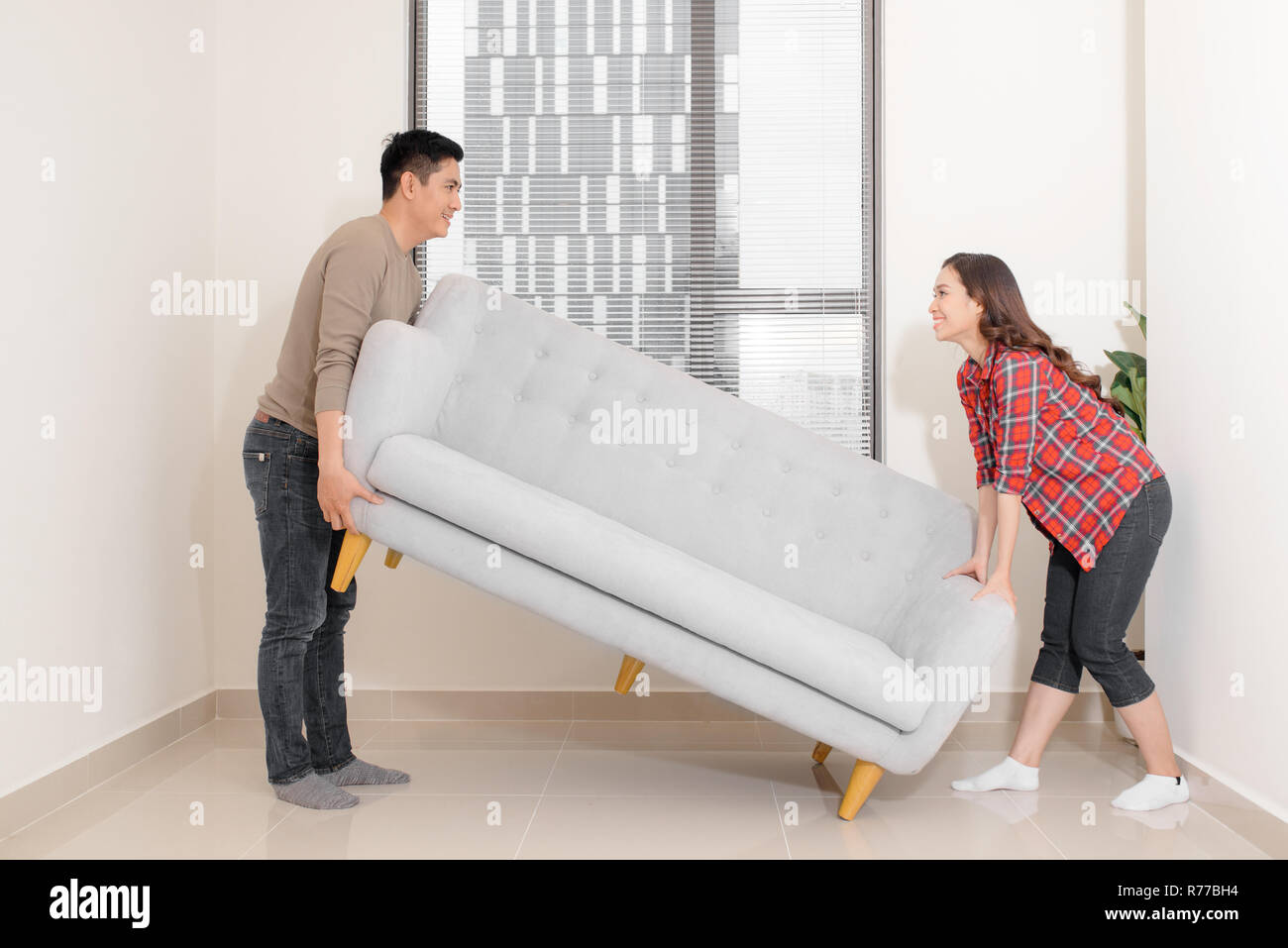 Smiling couple carrying modern chair together placing furniture moving ...