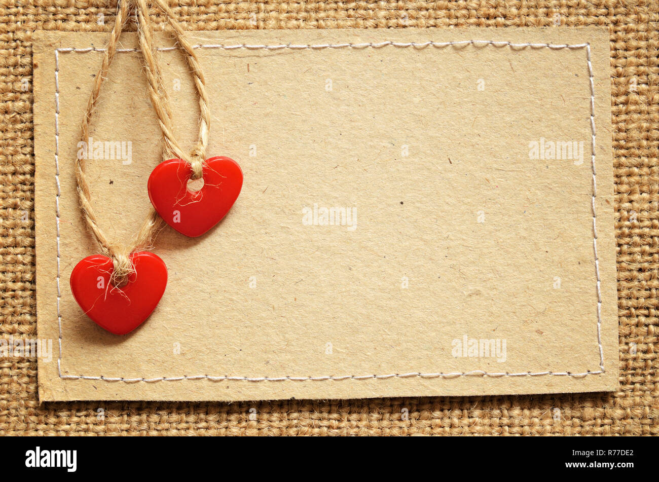 Two red plastic hearts and carton card on a canvas background Stock ...