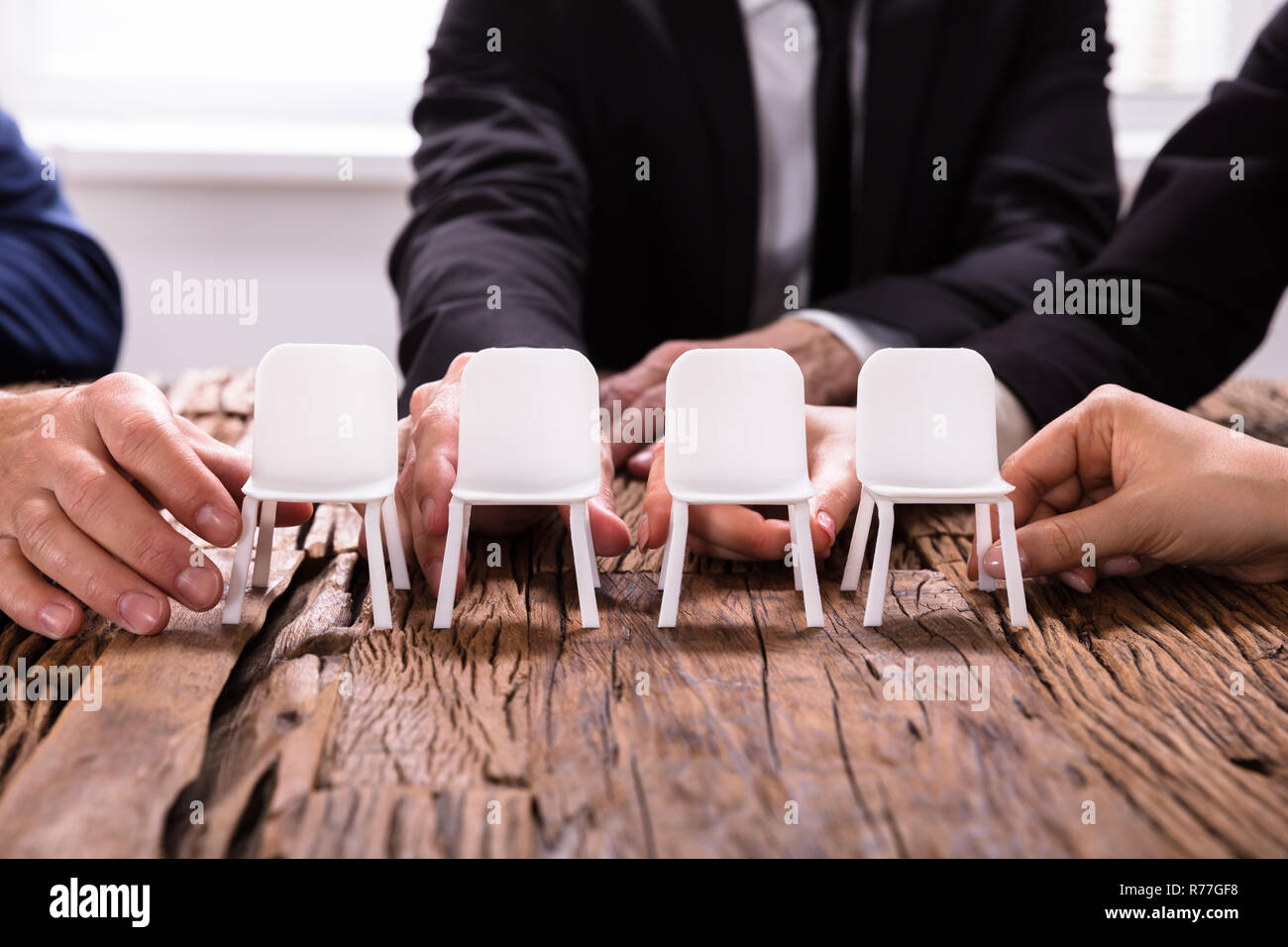 Businesspersons's Hands Arranging Chairs In A Row Stock Photo - Alamy