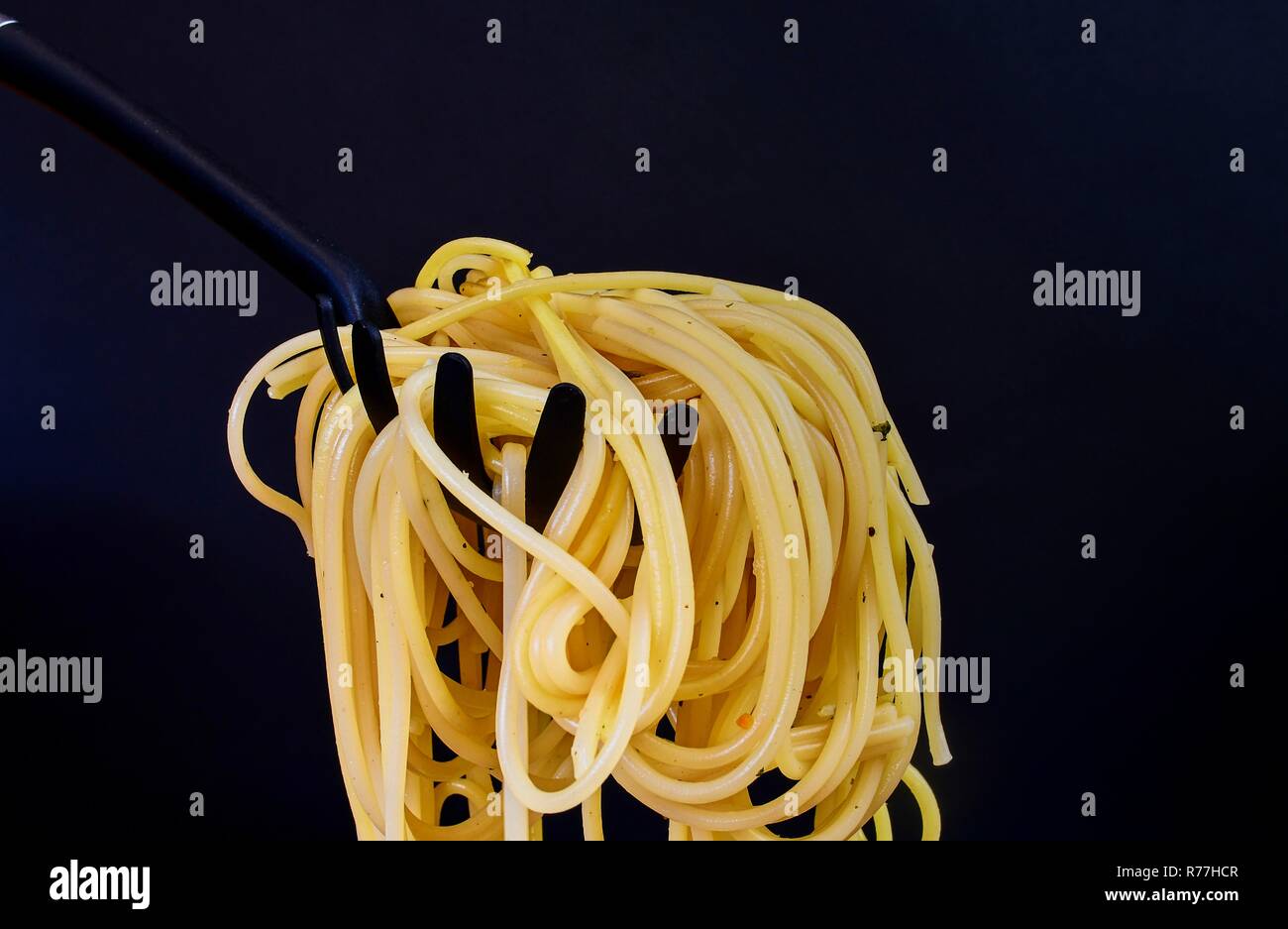Cooked spaghetti on spaghetti spoon. Spaghetti on black background ...