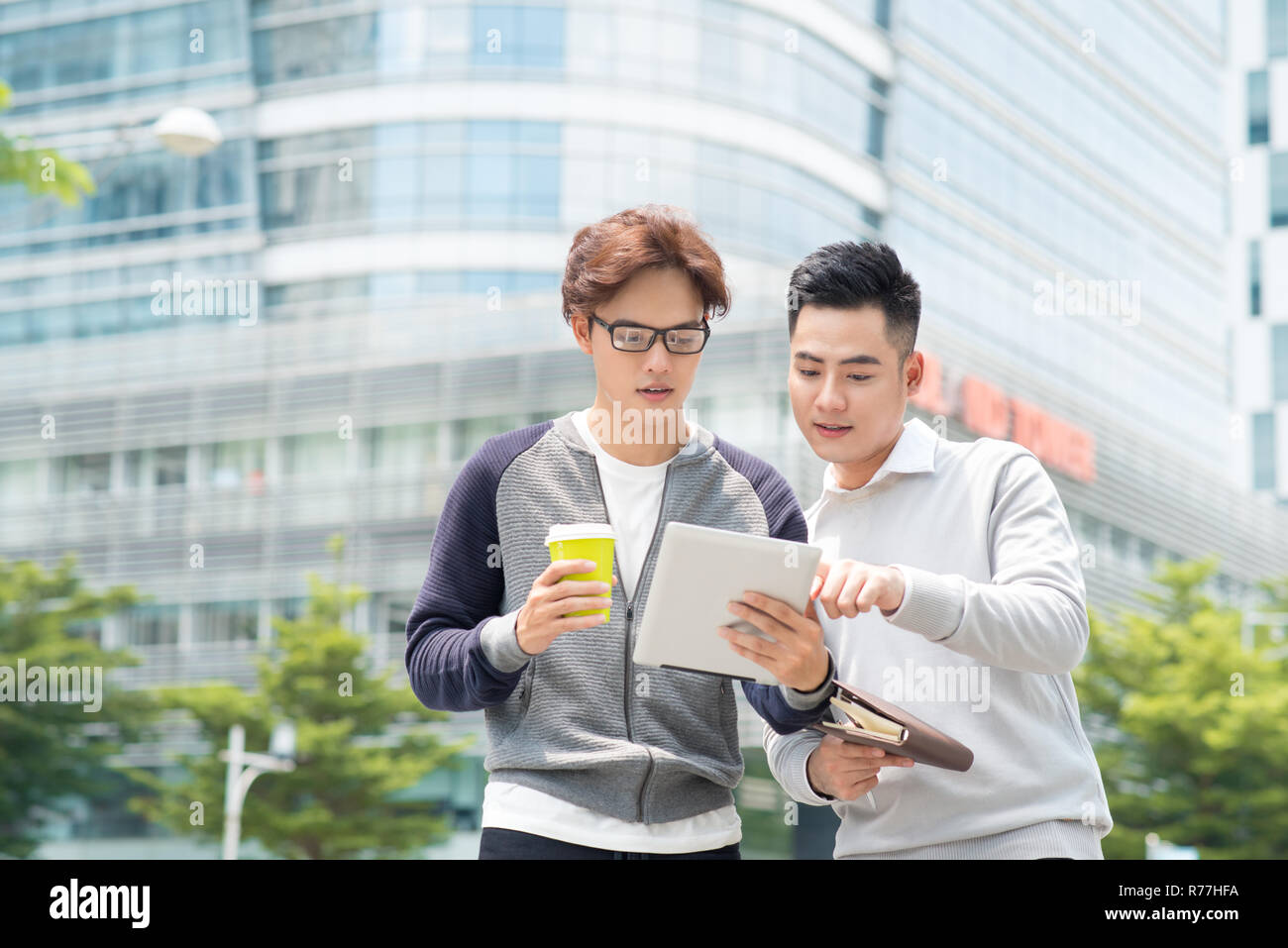 Two smiling male work coworkers outdoors talking together over a ...