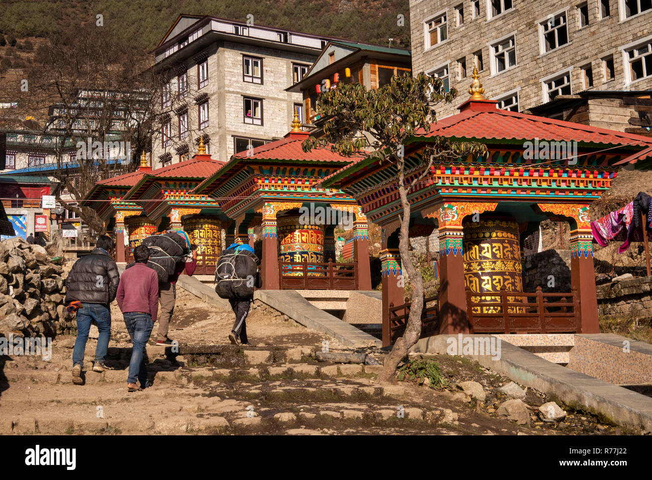 Nepal, Namche Bazar, porters carying loads up past colourful water ...