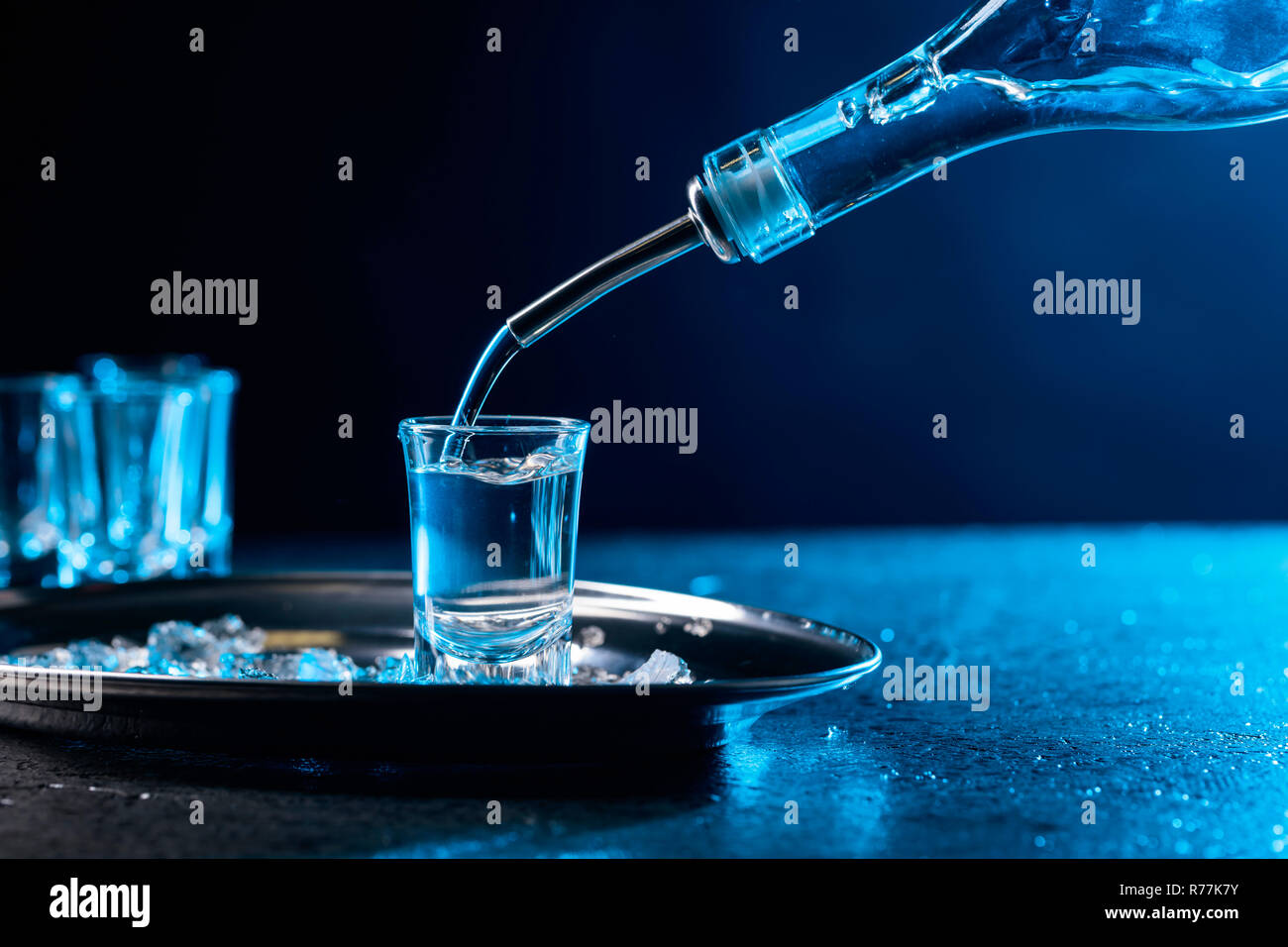 Vodka poured into a glass lit with blue backlight. Copy space.Chilled ...