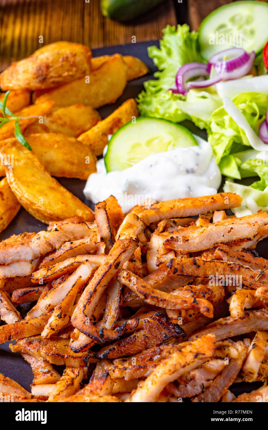 rustic gyros plate with green salad and potato wedges Stock Photo - Alamy