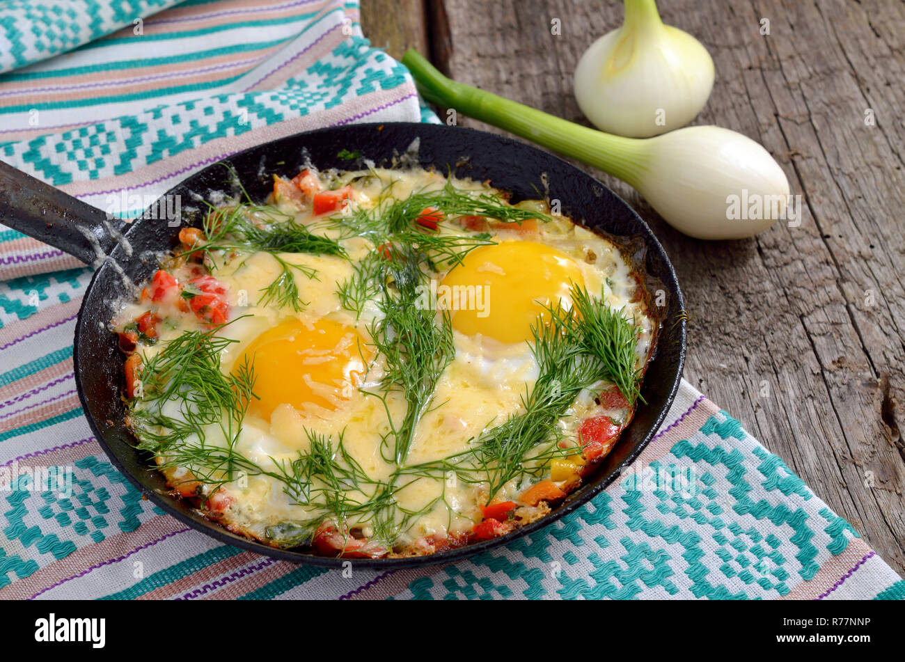 Fried eggs with greens, vegetables and cheese on a frying pan Stock ...