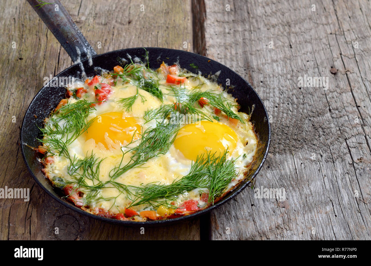 Fried eggs with greens, vegetables and cheese on a frying pan Stock ...