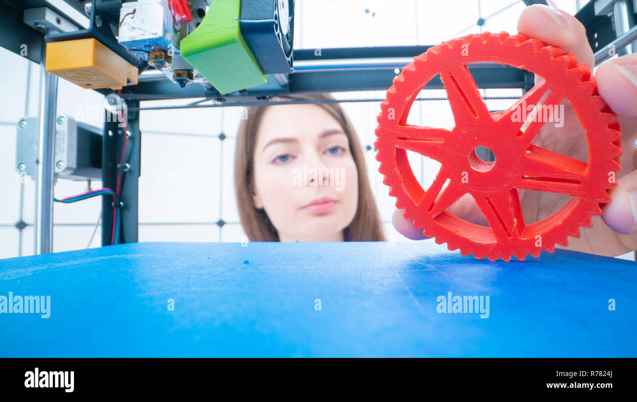 Young women designer in 3d printing lab. Girl takes the finished detail ...