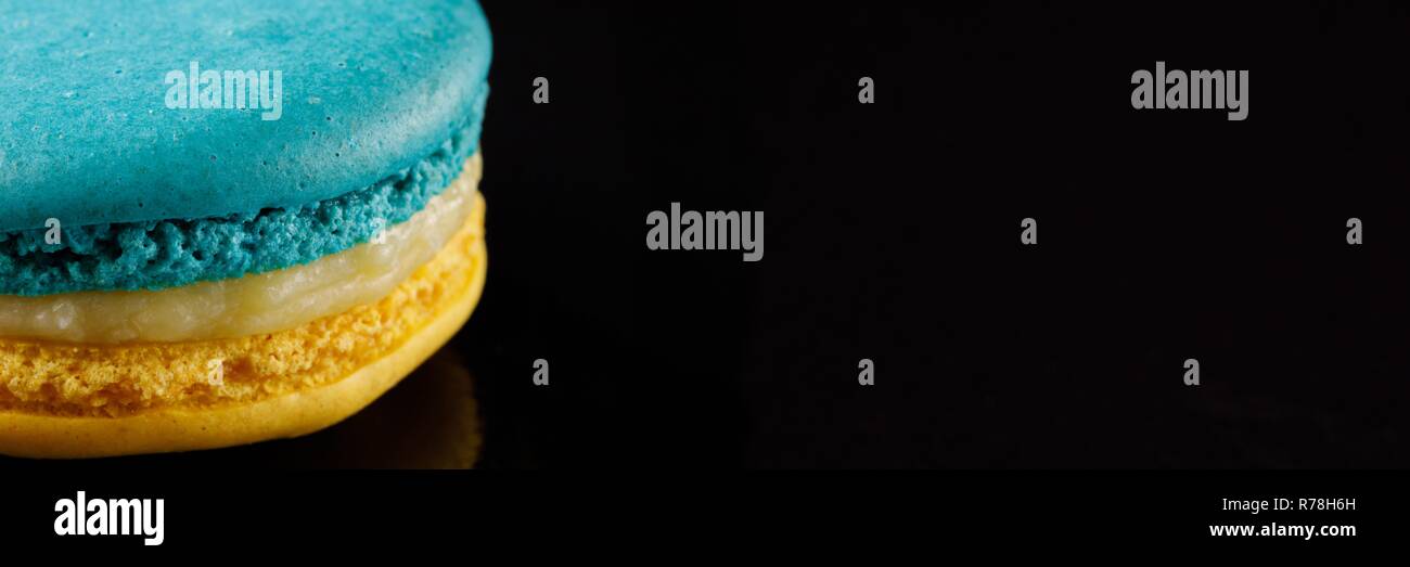 Bright juicy delicious macarons of blue and yellow color on a black ...