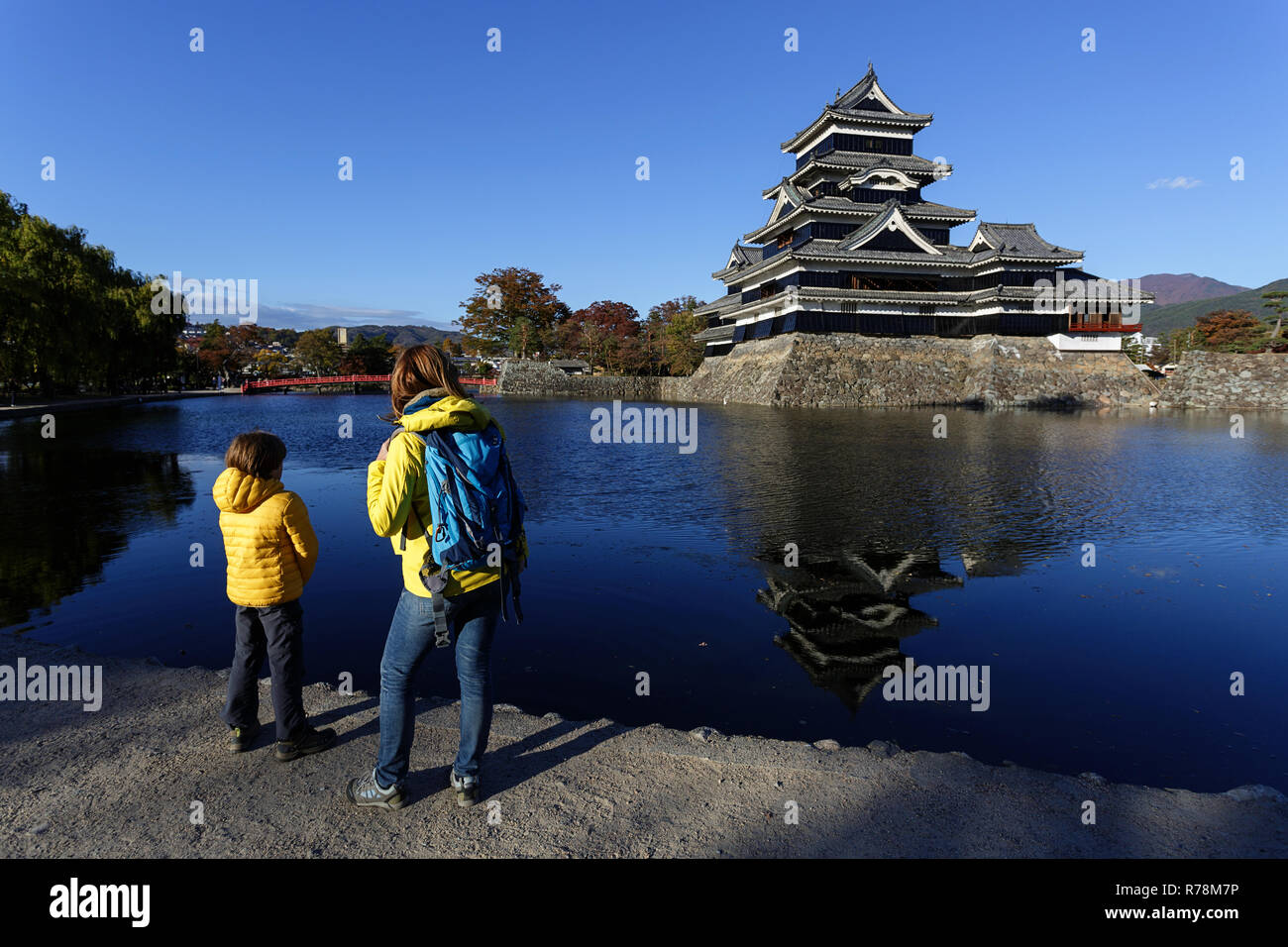 Mother and son in yellow jackets, tourists, standing at the lake in ...