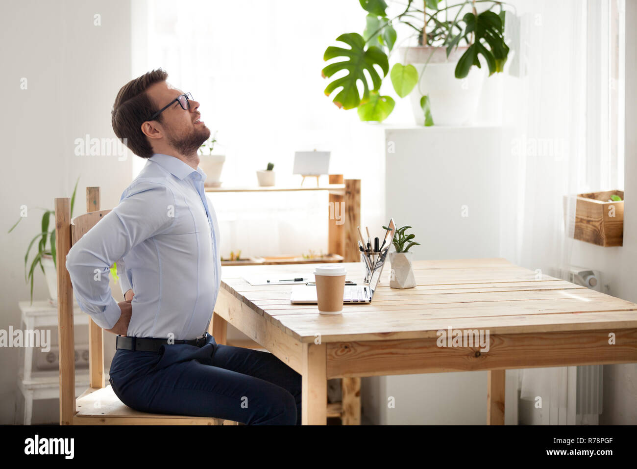 Tired male worker stretching in chair suffering from back pain Stock ...