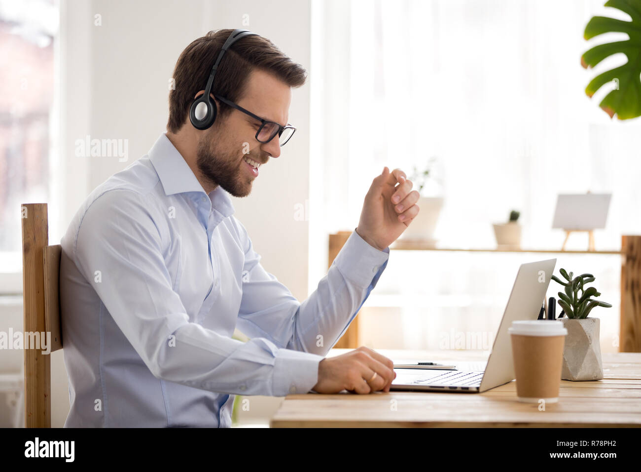 Happy male employee in headset listen to music online Stock Photo - Alamy