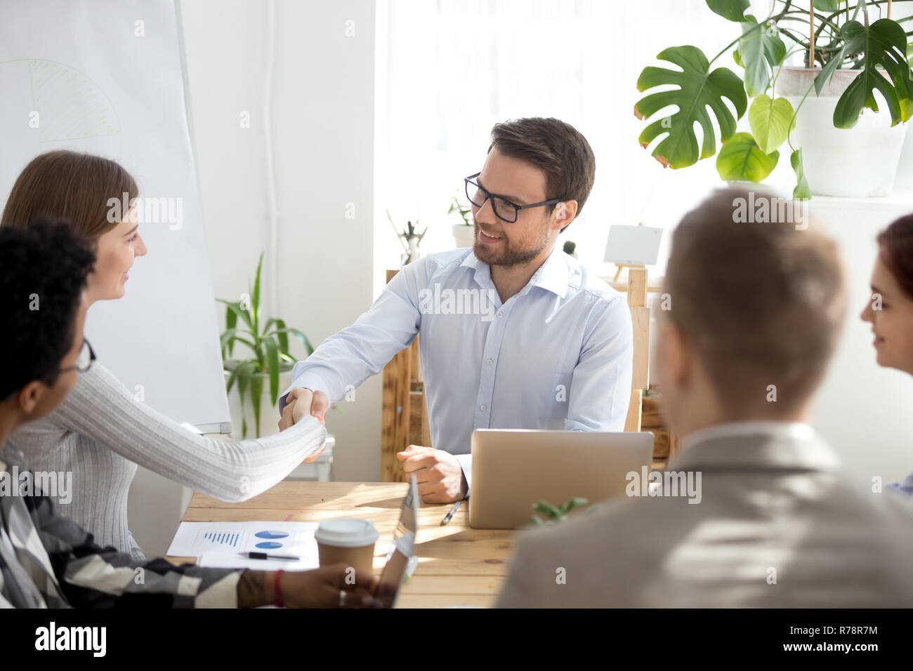 Smiling businessman handshake female employee at meeting Stock Photo ...