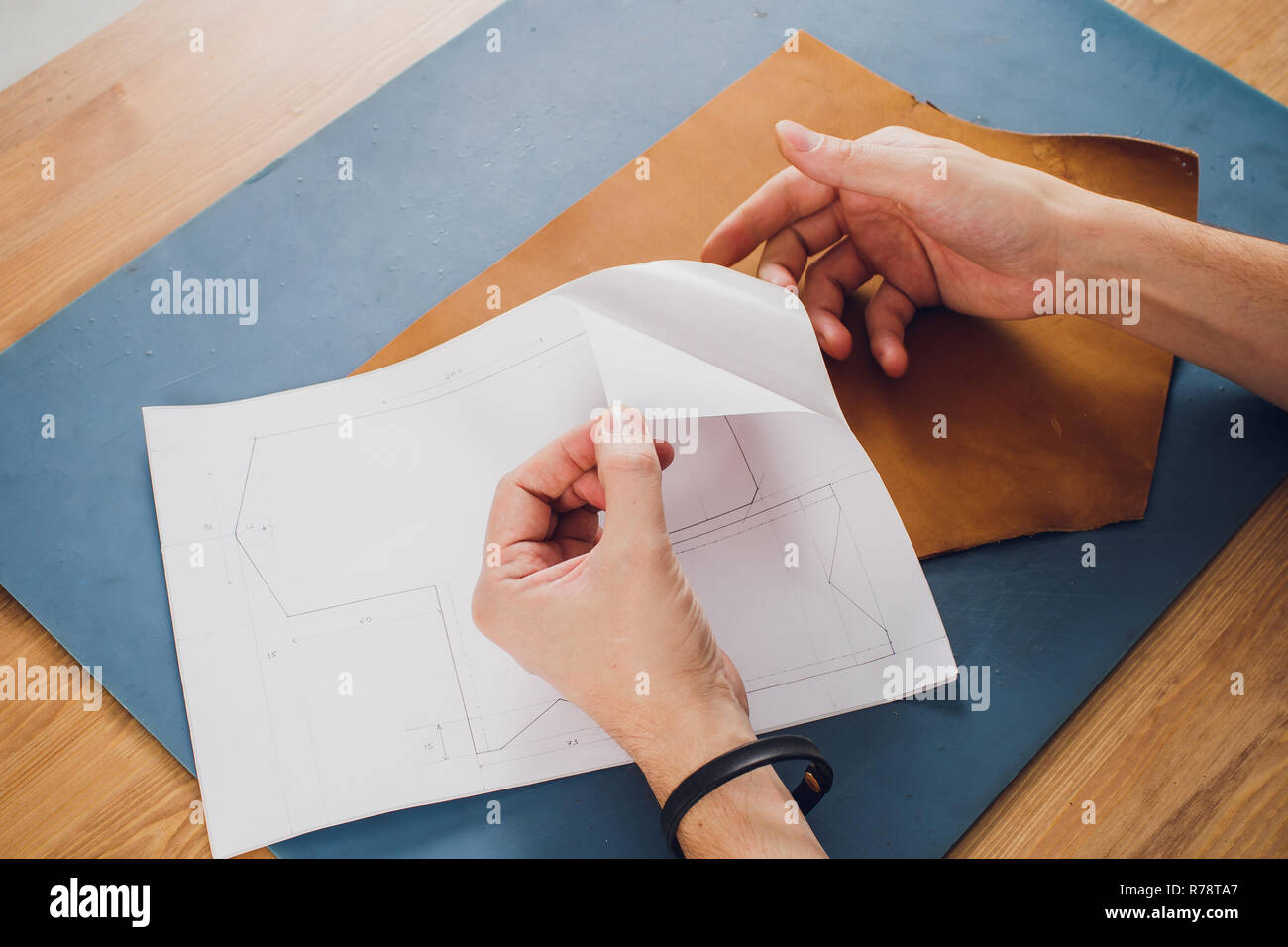 Working day in studio. Man leather worker drawing sketch of purse with ...