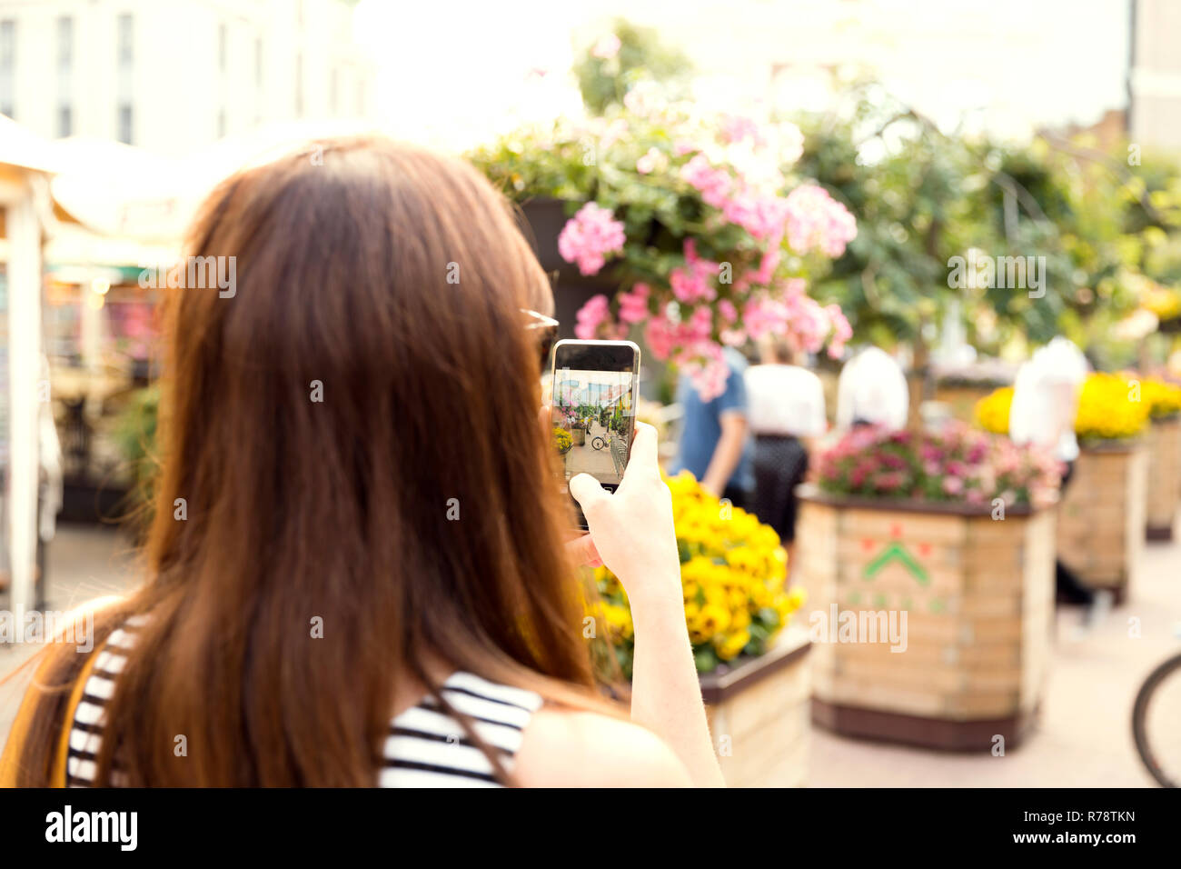 Woman on city tour taking picture of beautiful cafe flowers with her ...