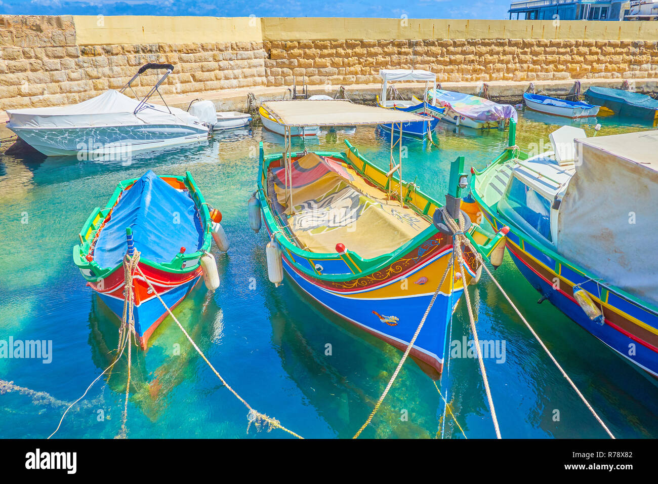 The traditional Maltese colorful wooden luzzu boats at small harbour ...