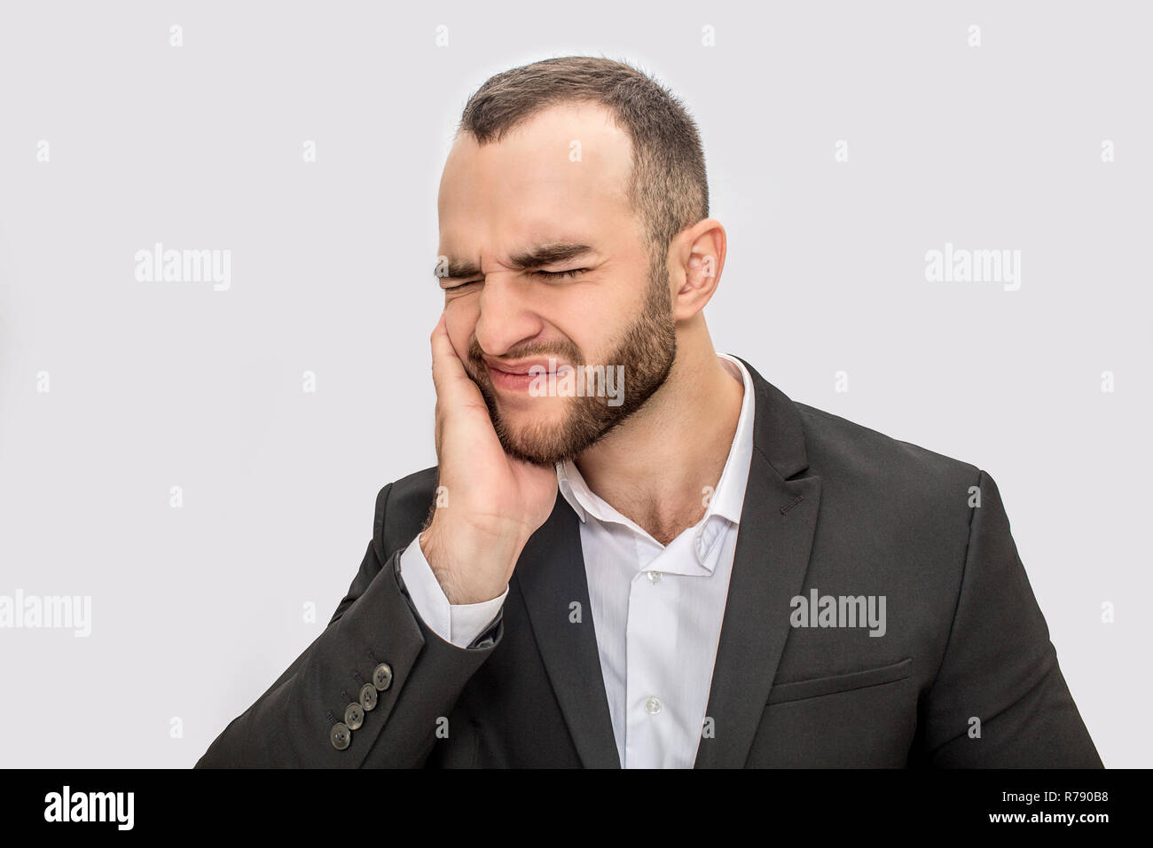 Young bearded man suffer from tooth ache. He holds hand on cheek and ...