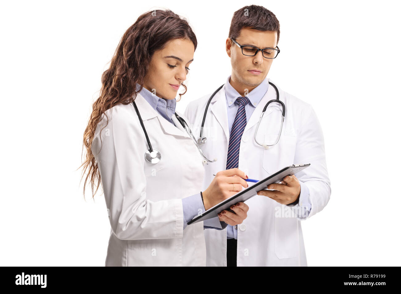Two young doctors looking at a paper on a clipboard isolated on white ...