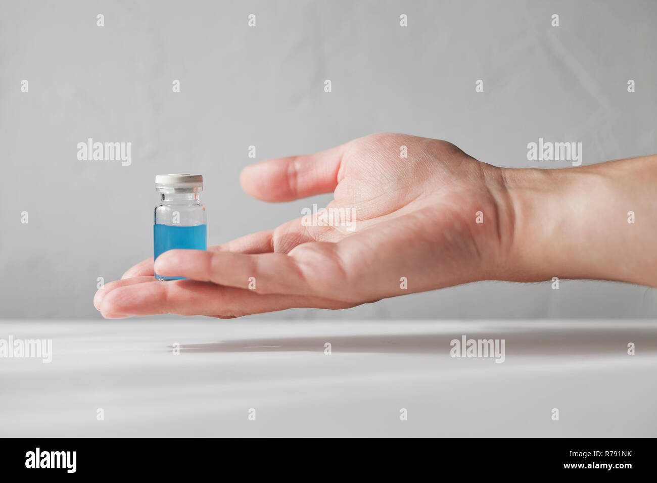 Human hand holding an old glass vial filled with cyan blue liquid on ...