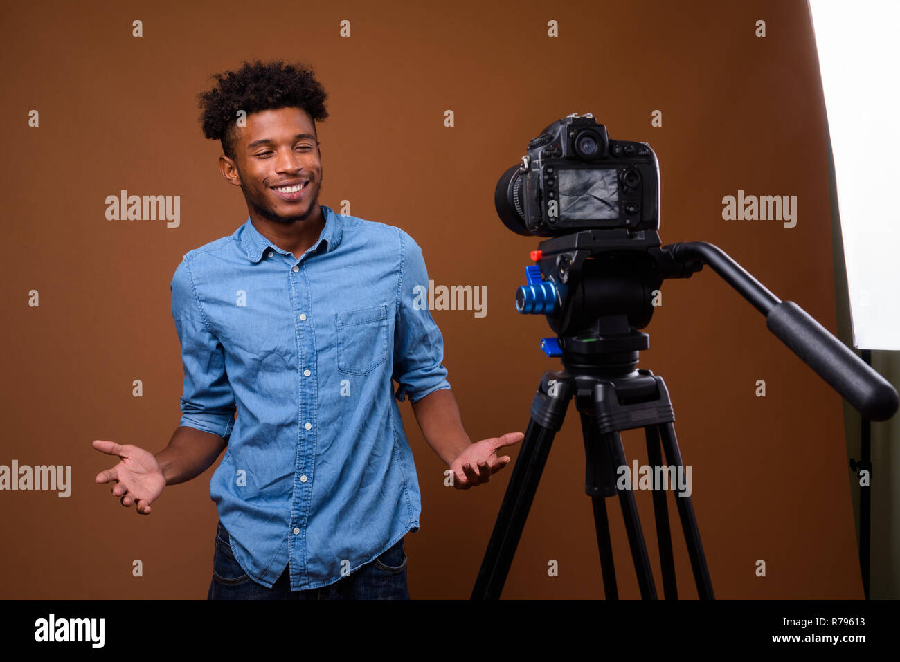 Young handsome African man vlogging with DSLR camera in studio Stock ...