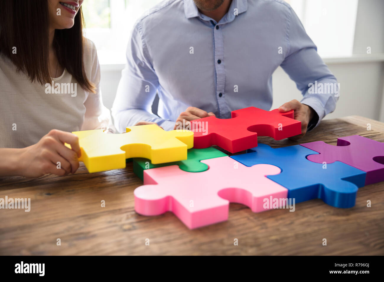 Two Businesspeople Solving Jigsaw Puzzle Stock Photo - Alamy