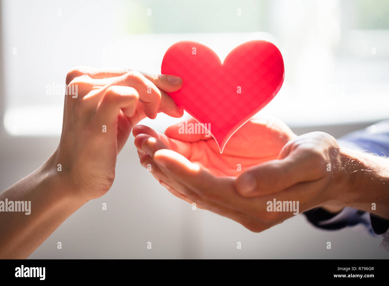 Woman Giving Heart On Man's Hand Stock Photo - Alamy