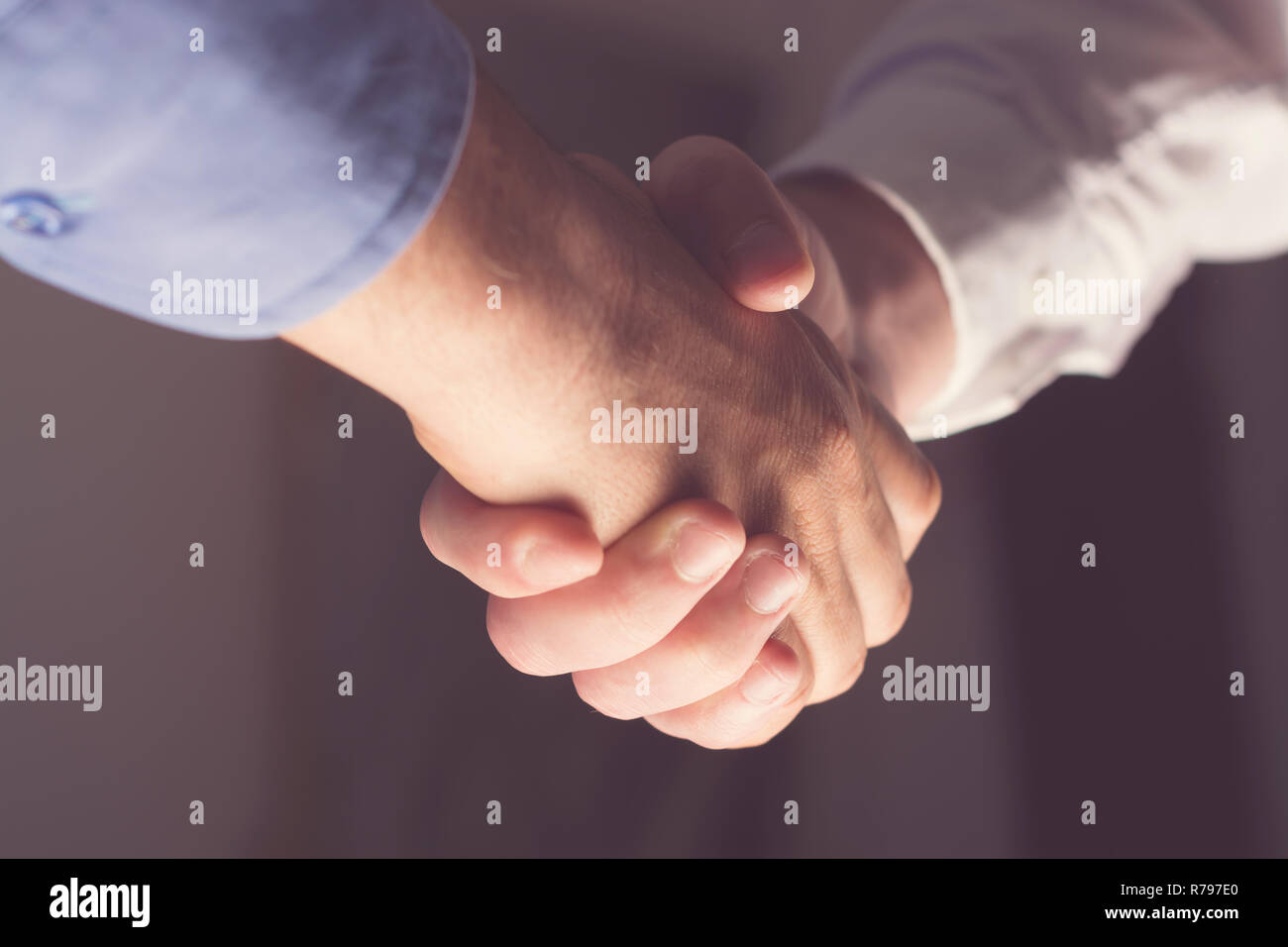 Handshaking of two friends people. Low light Stock Photo - Alamy