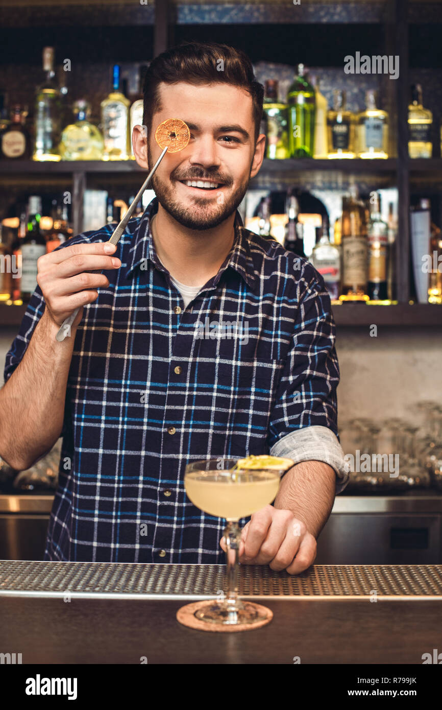 Young bartender standing at bar counter covering eye with circle of ...