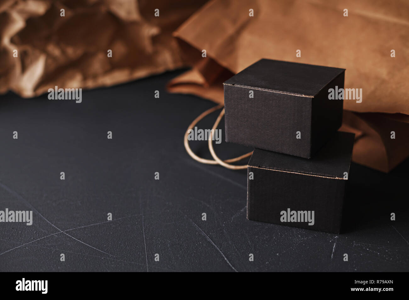 Two matte black carton gift boxes laying on a black painted scratched ...