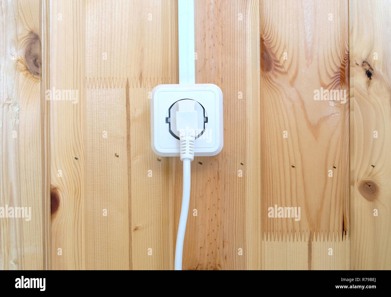 White electric plug in socket on wooden wall with vertical planks front ...
